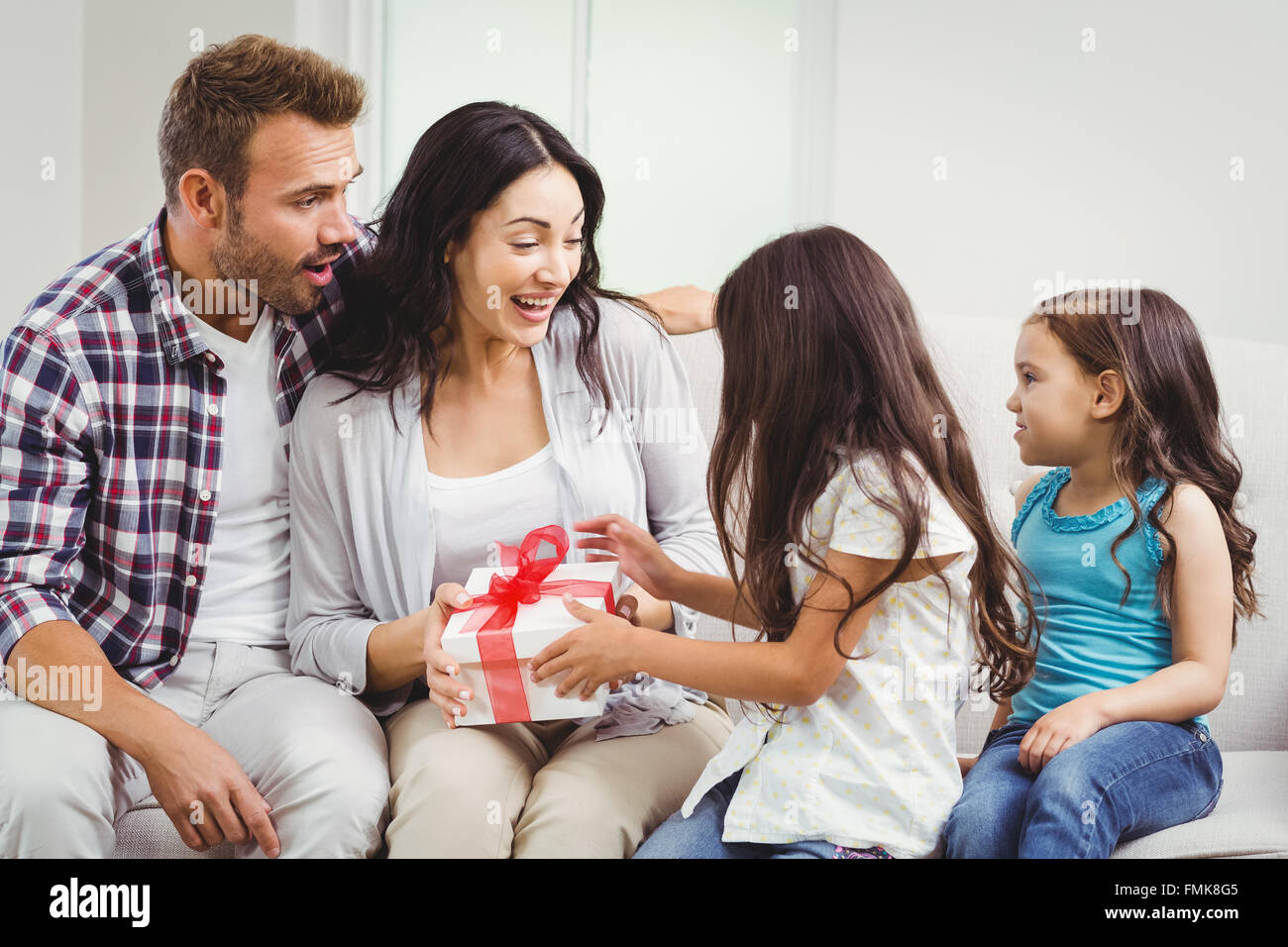 Daughters giving gift to surprised parents Stock Photo - Alamy