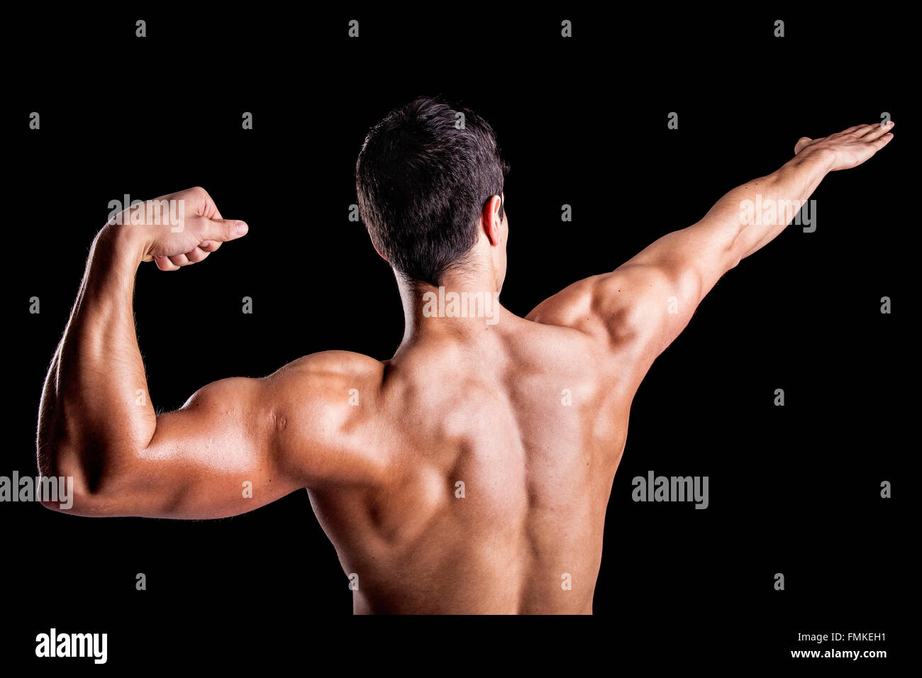 Muscle young man showing his back muscles against a dark background ...