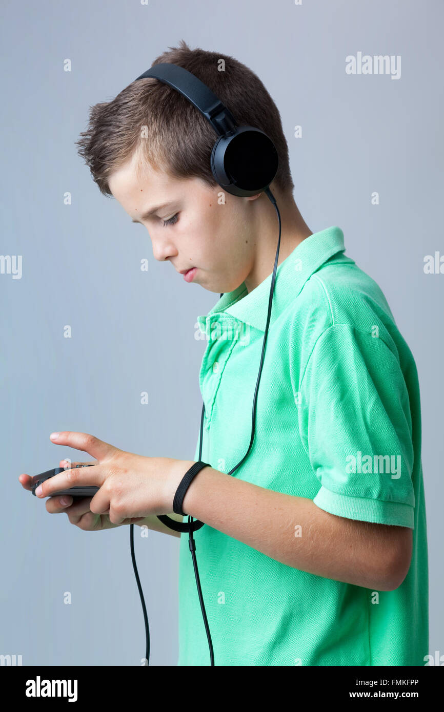 Boy playing game console against grey background Stock Photo - Alamy