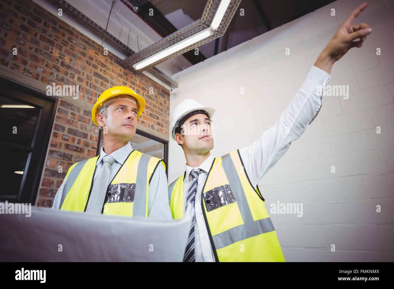 Architect pointing with colleague holding blueprint Stock Photo - Alamy