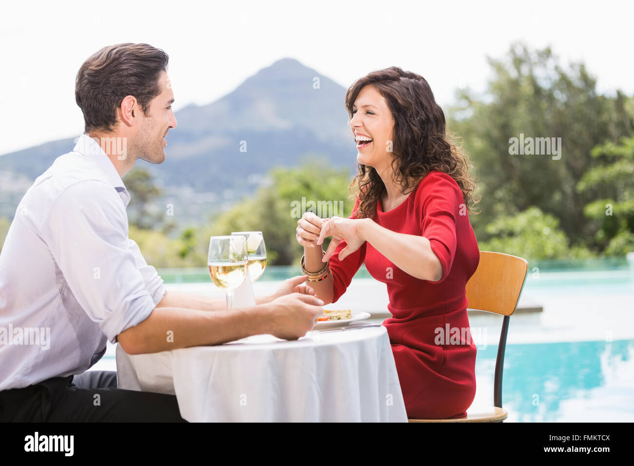 Cheerful couple sitting by swimming pool Stock Photo - Alamy