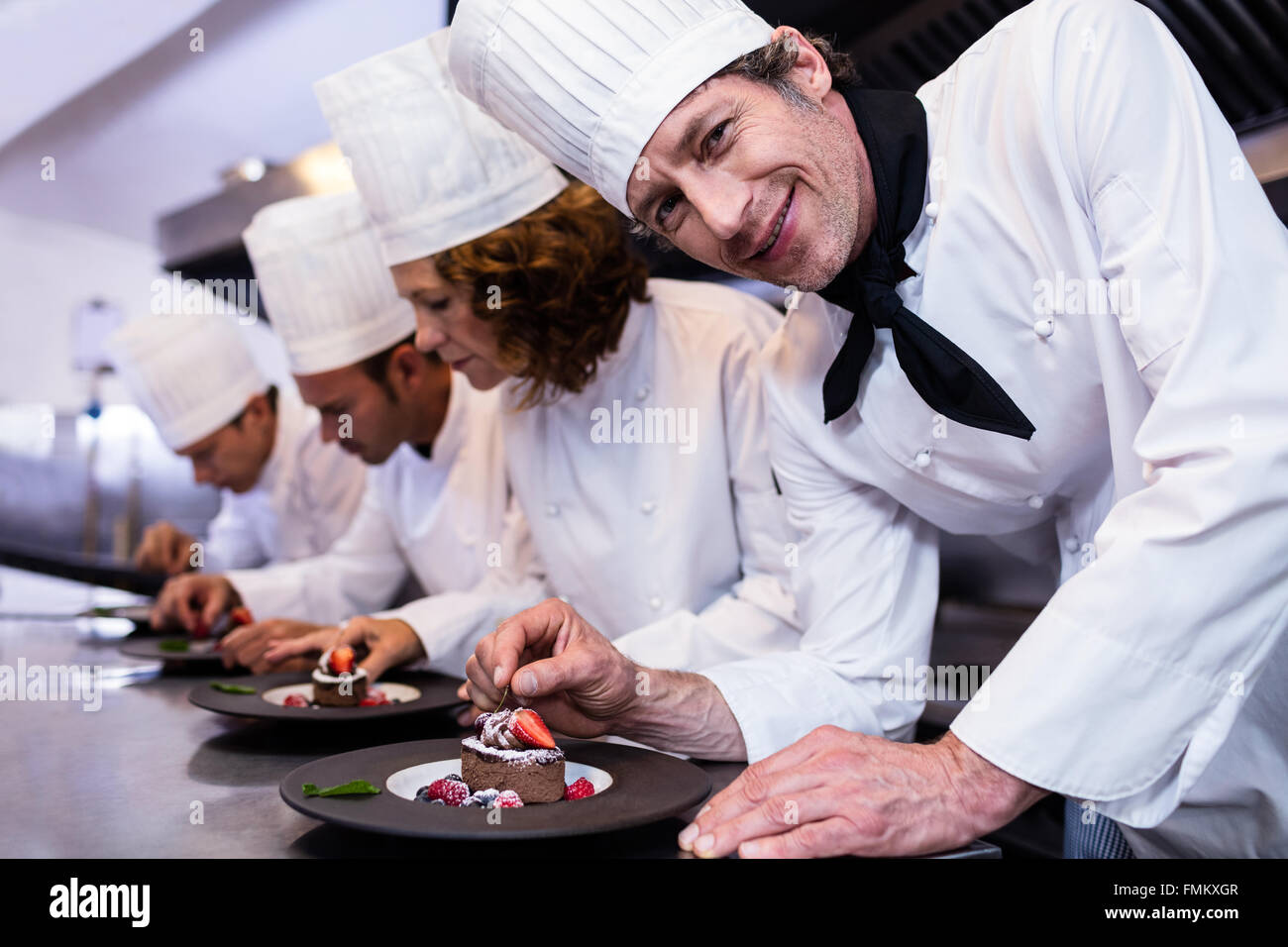 Chefs team finishing dessert plates Stock Photo - Alamy