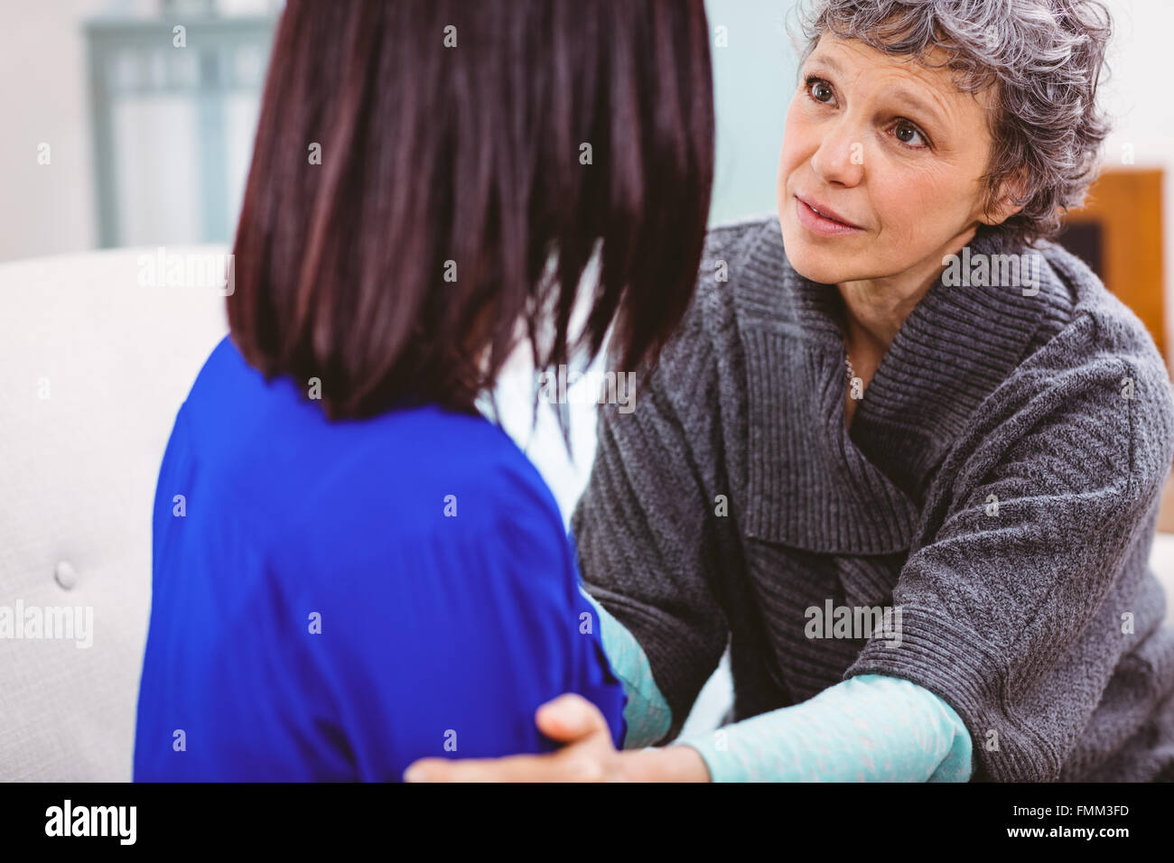 Mother talking to daughter sitting on sofa Stock Photo - Alamy