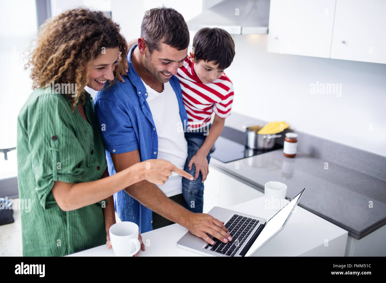 Parents using laptop with son in kitchen Stock Photo - Alamy