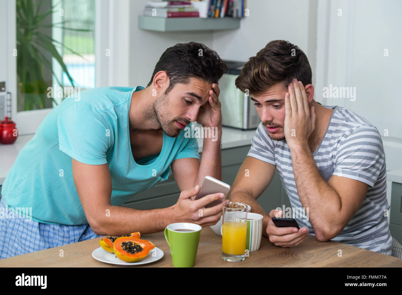 Frustrated male friends using phone Stock Photo - Alamy