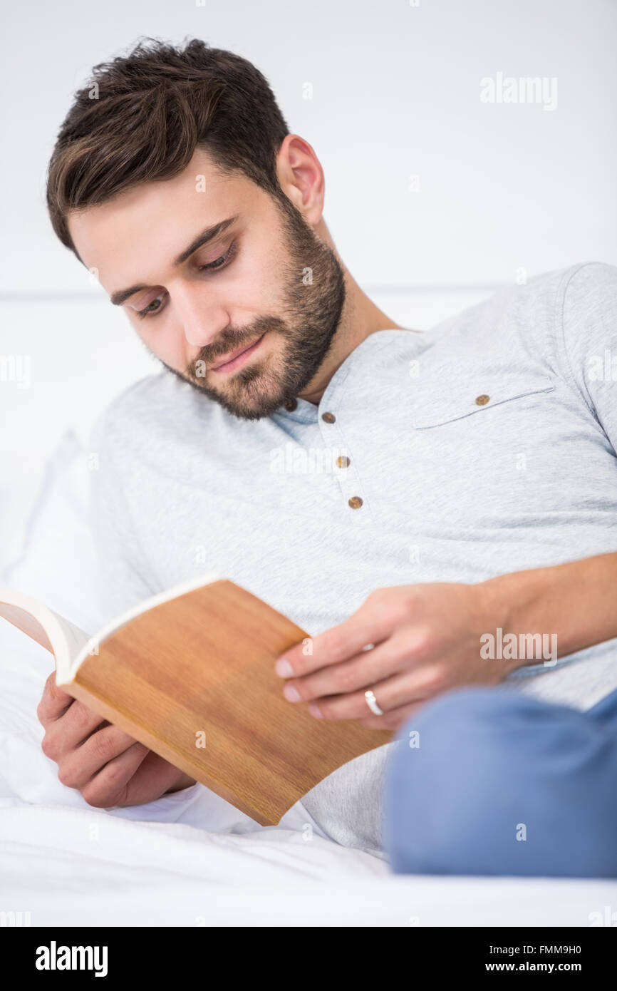 Man reading book on bed at home Stock Photo - Alamy