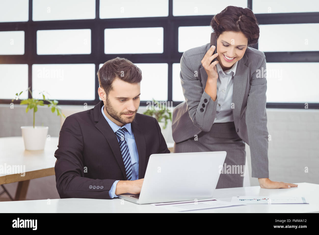 Business people with mobile phone and laptop in office Stock Photo - Alamy