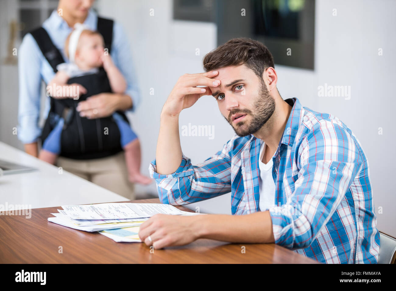 Tensed man with wife and baby in background Stock Photo - Alamy