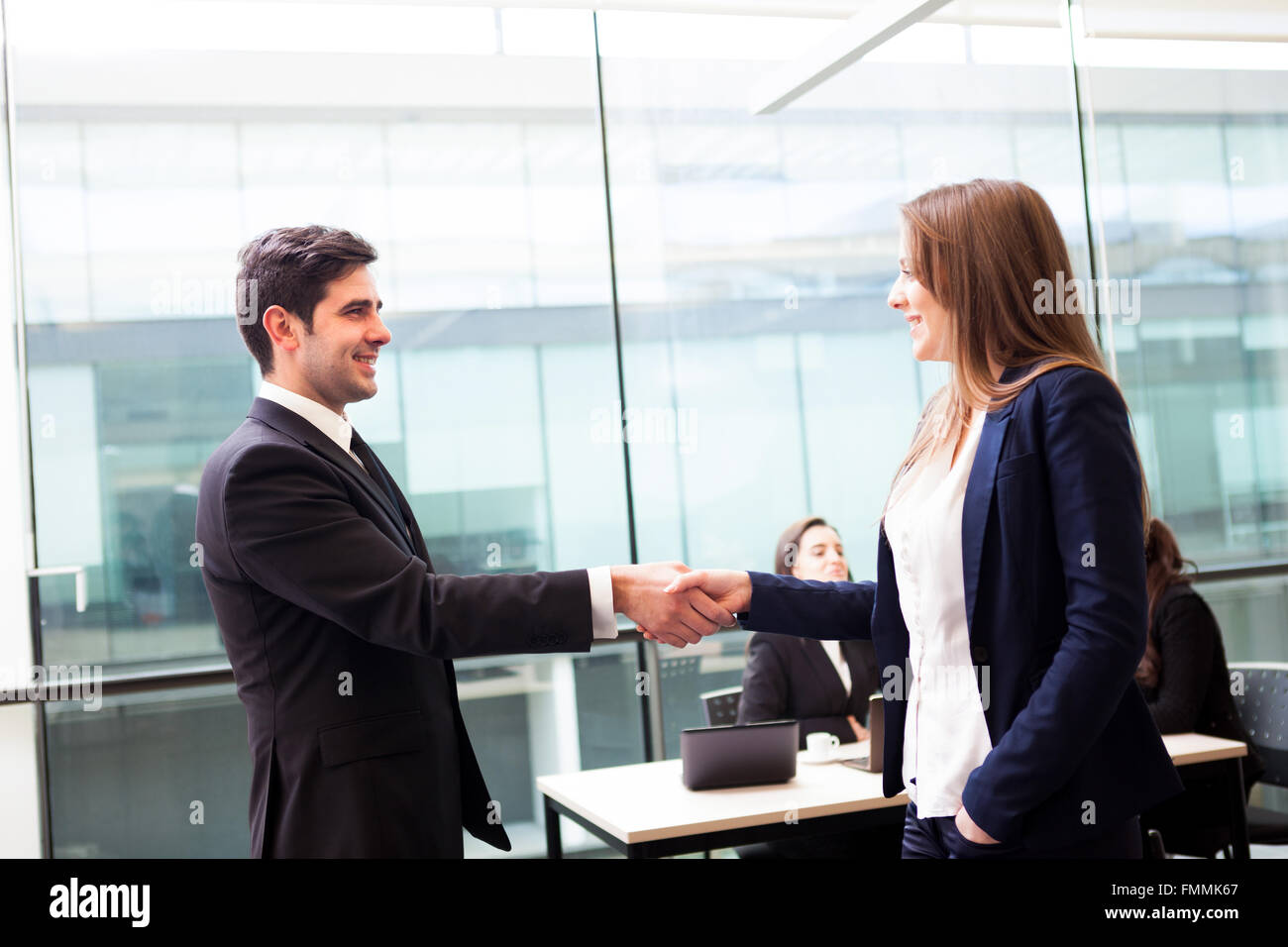 Business handshake at modern office with bussiness people on background ...