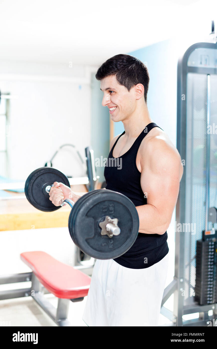Smiling handsome man lifting heavy free weights at the gym Stock Photo ...