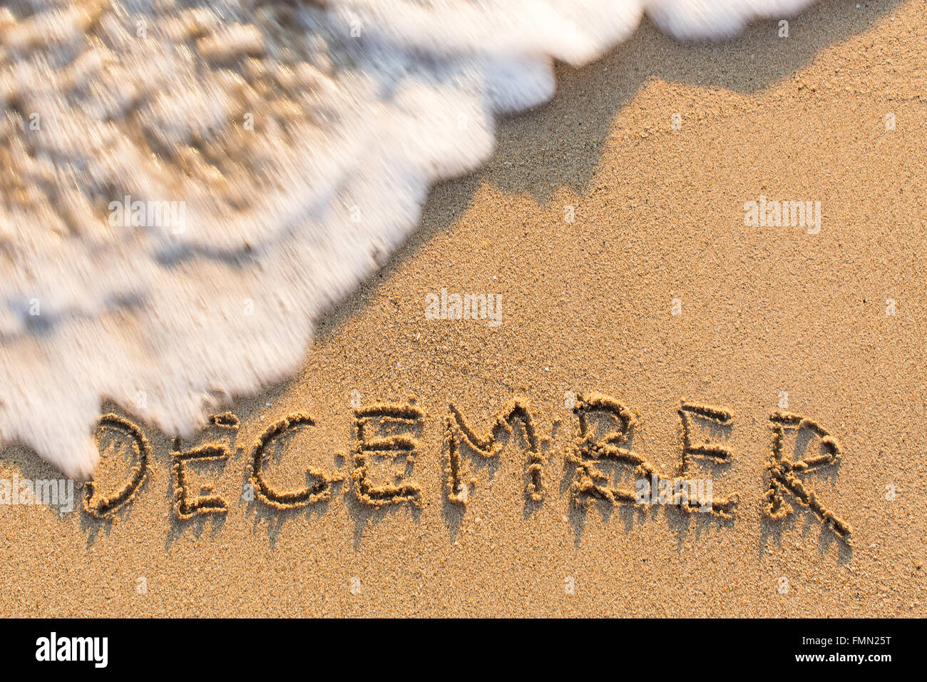 December - word drawn on the sand beach with the soft wave Stock Photo ...