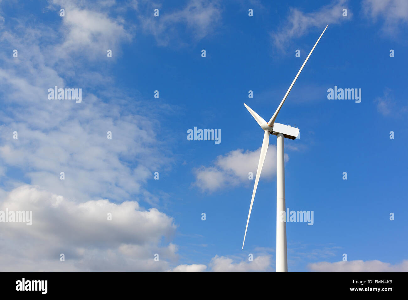 White wind turbine generating electricity on cloudy sky Stock Photo - Alamy
