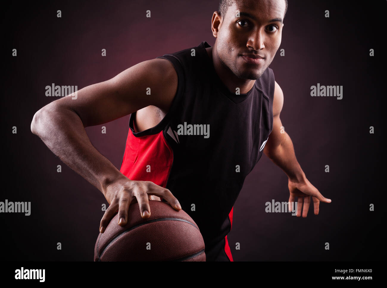 Portrait of a young male basketball player against black background ...