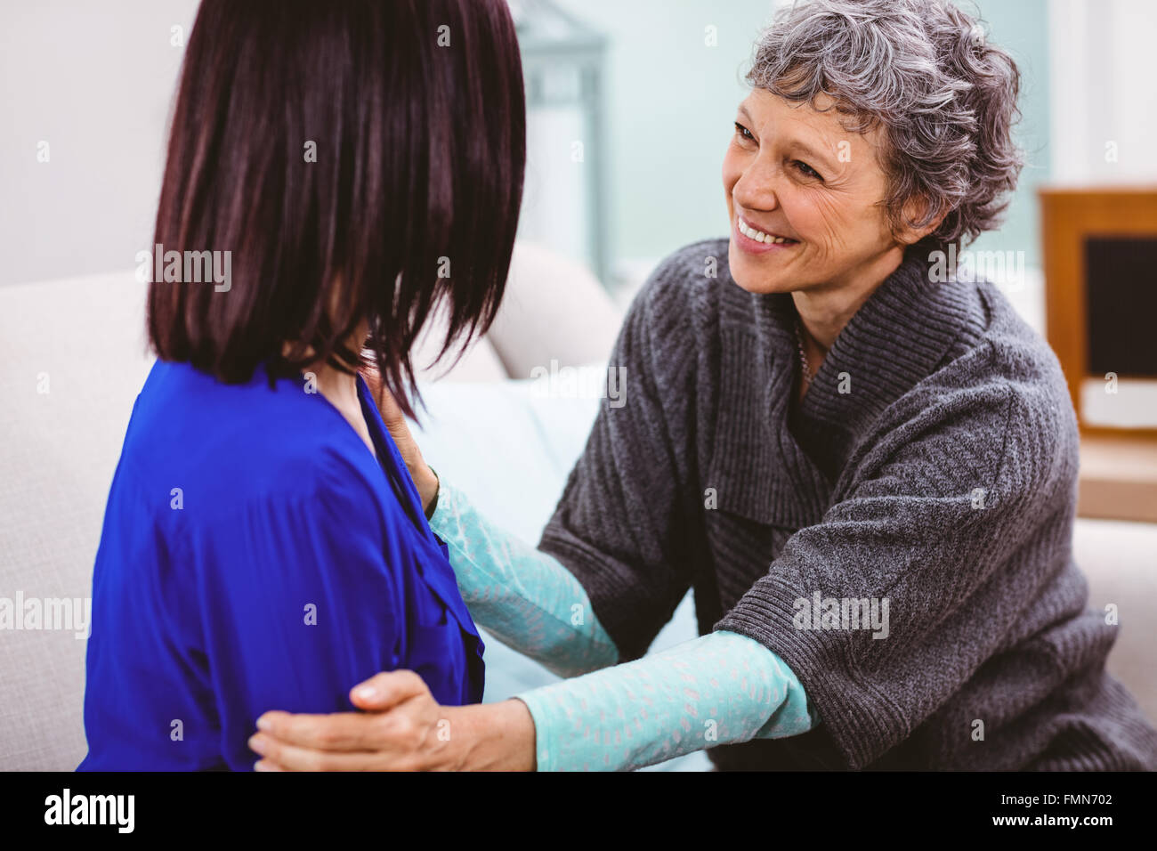 Happy mother talking to daughter sitting on sofa Stock Photo - Alamy
