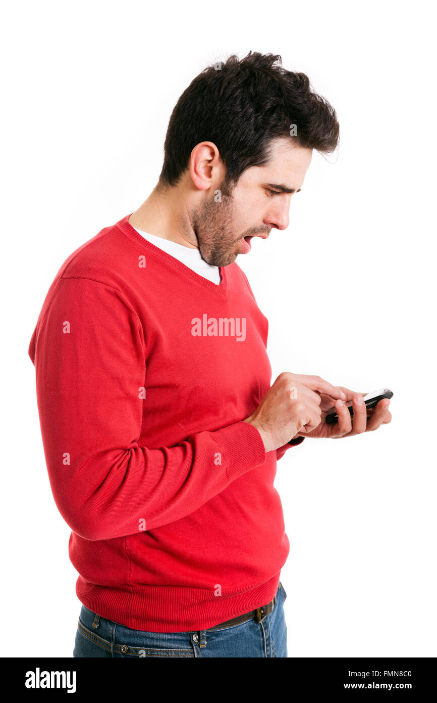 Surprised young man looking at his smart phone while text messaging ...