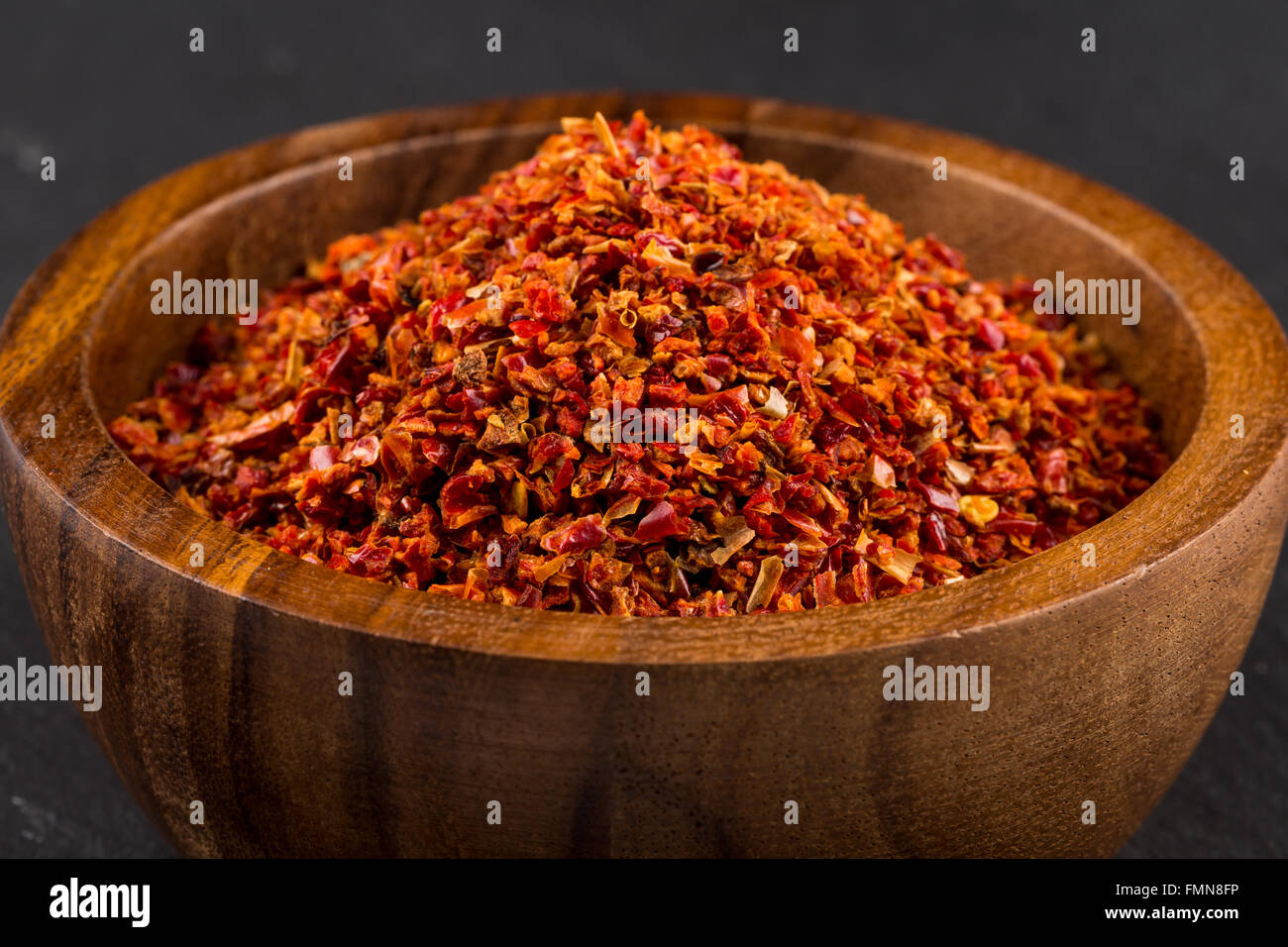 Crushed red chili pepper in wooden bowl on white background Stock Photo ...