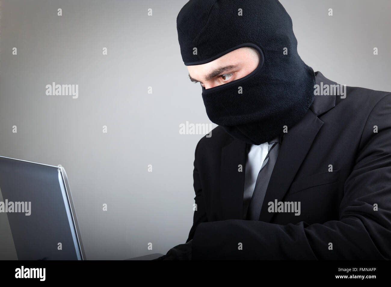 Computer hacker in suit and tie over grey background Stock Photo - Alamy
