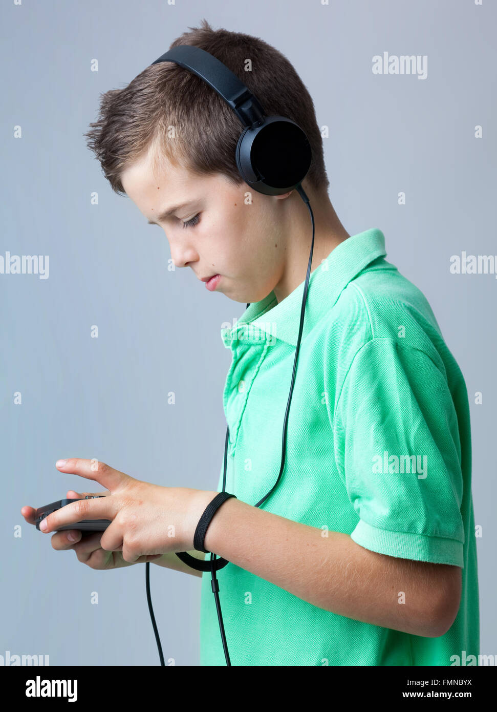Boy playing game console against grey background Stock Photo - Alamy