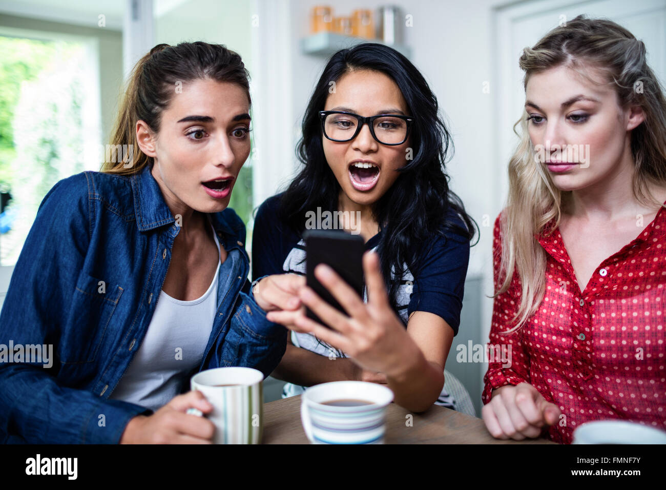 Female friends shocked while looking in mobile phone Stock Photo - Alamy