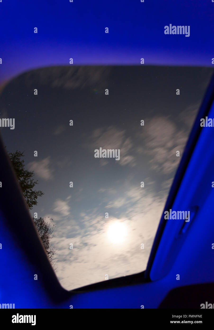 A photo of the night sky with a full moon looking through the sunroof ...