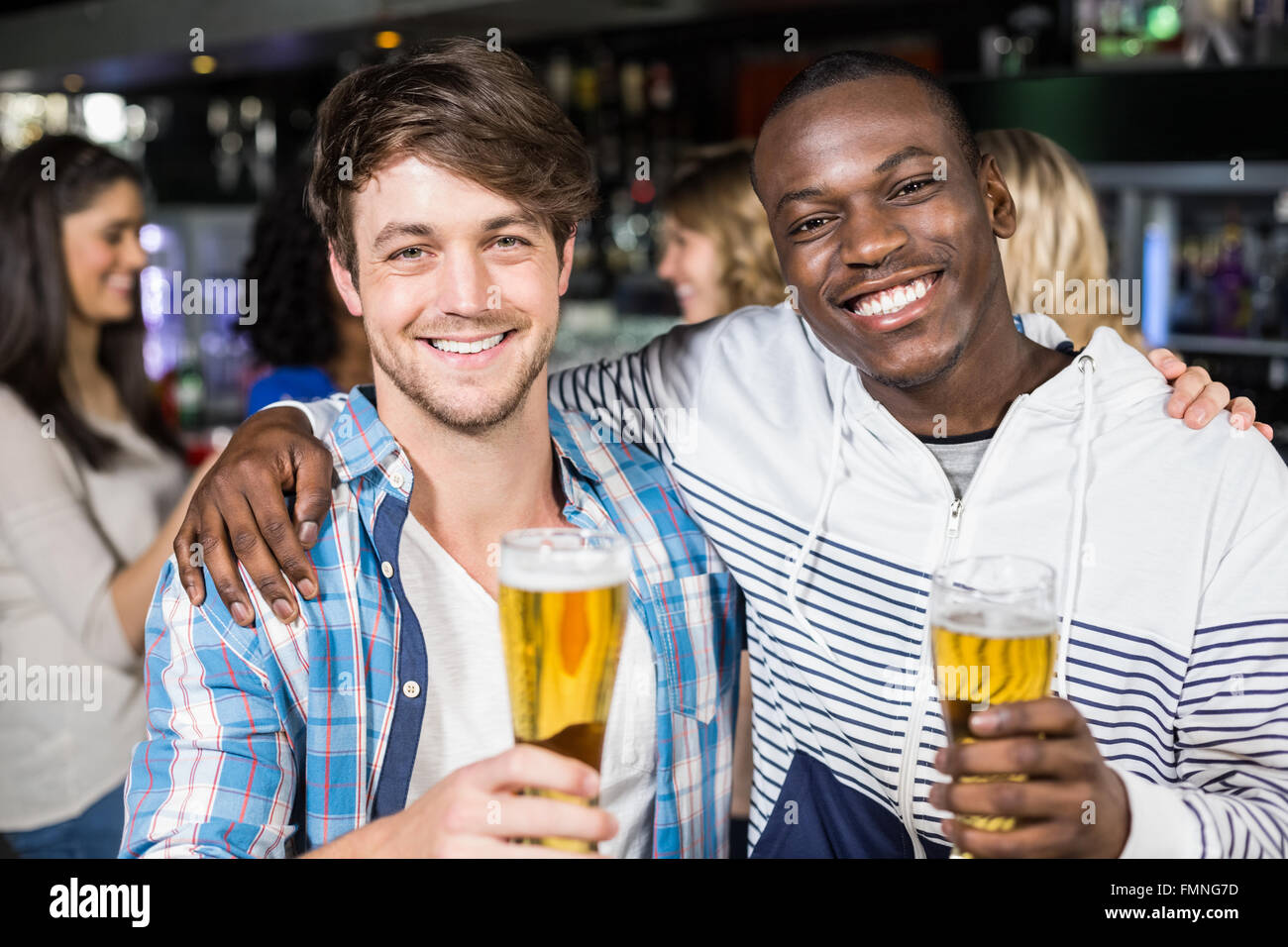 Smiling friends showing beer with their friends Stock Photo - Alamy