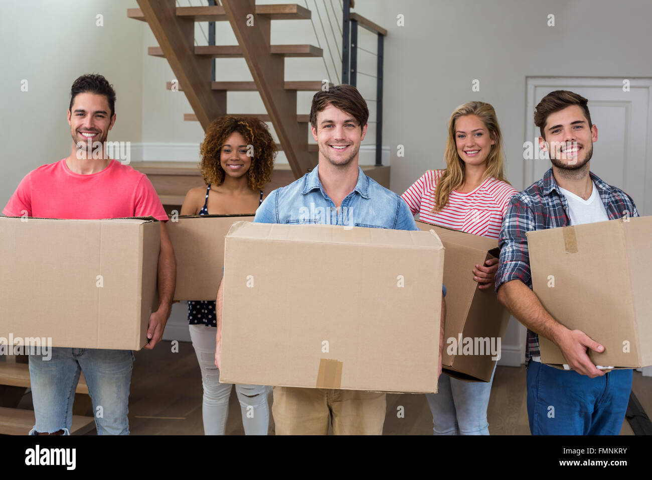 Friends smiling while carrying cardboard boxes Stock Photo - Alamy