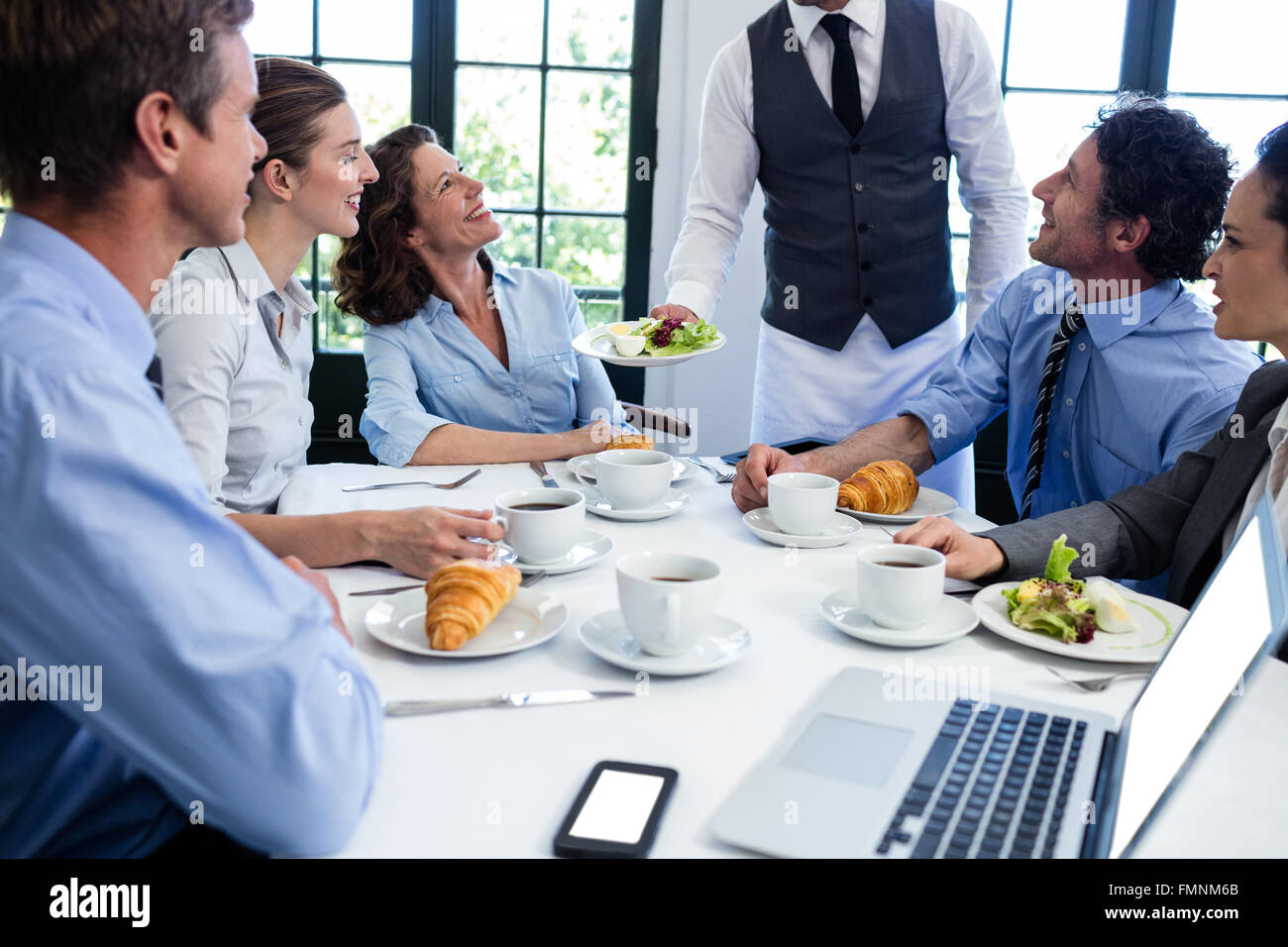 Waiter serving salad to business people Stock Photo - Alamy