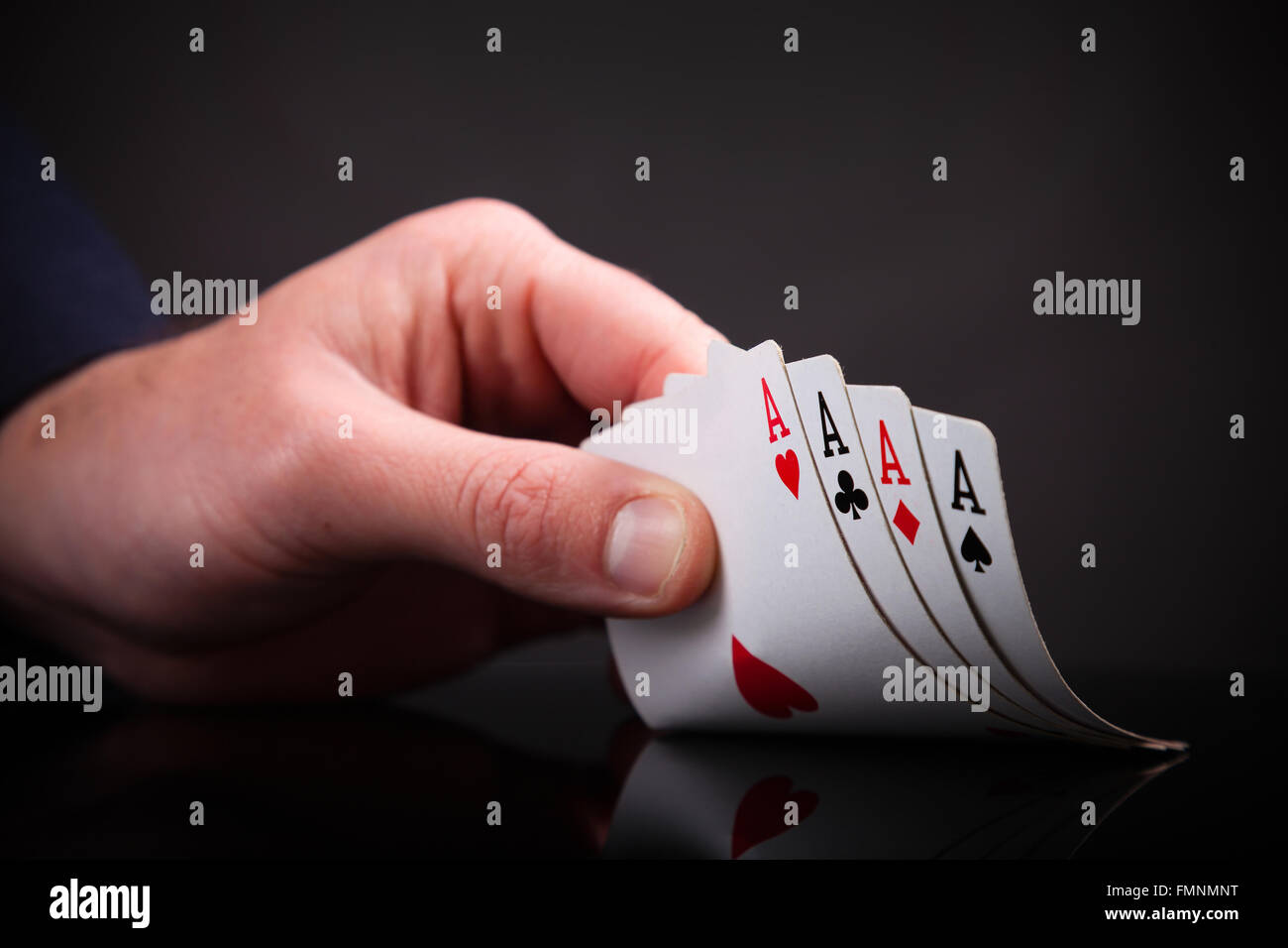Four aces in the hand on black background Stock Photo - Alamy