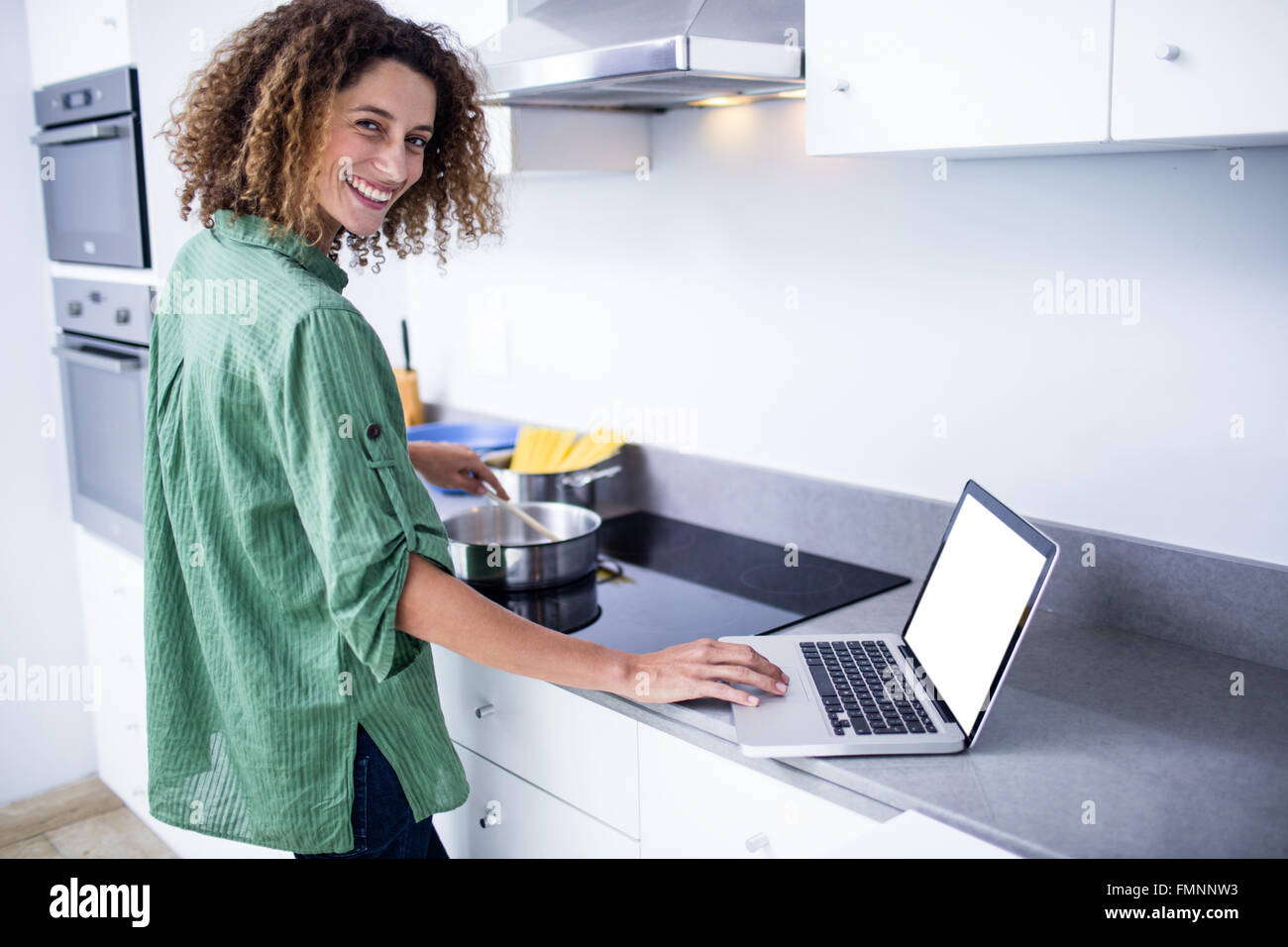 Portrait of woman working on laptop while cooking Stock Photo - Alamy