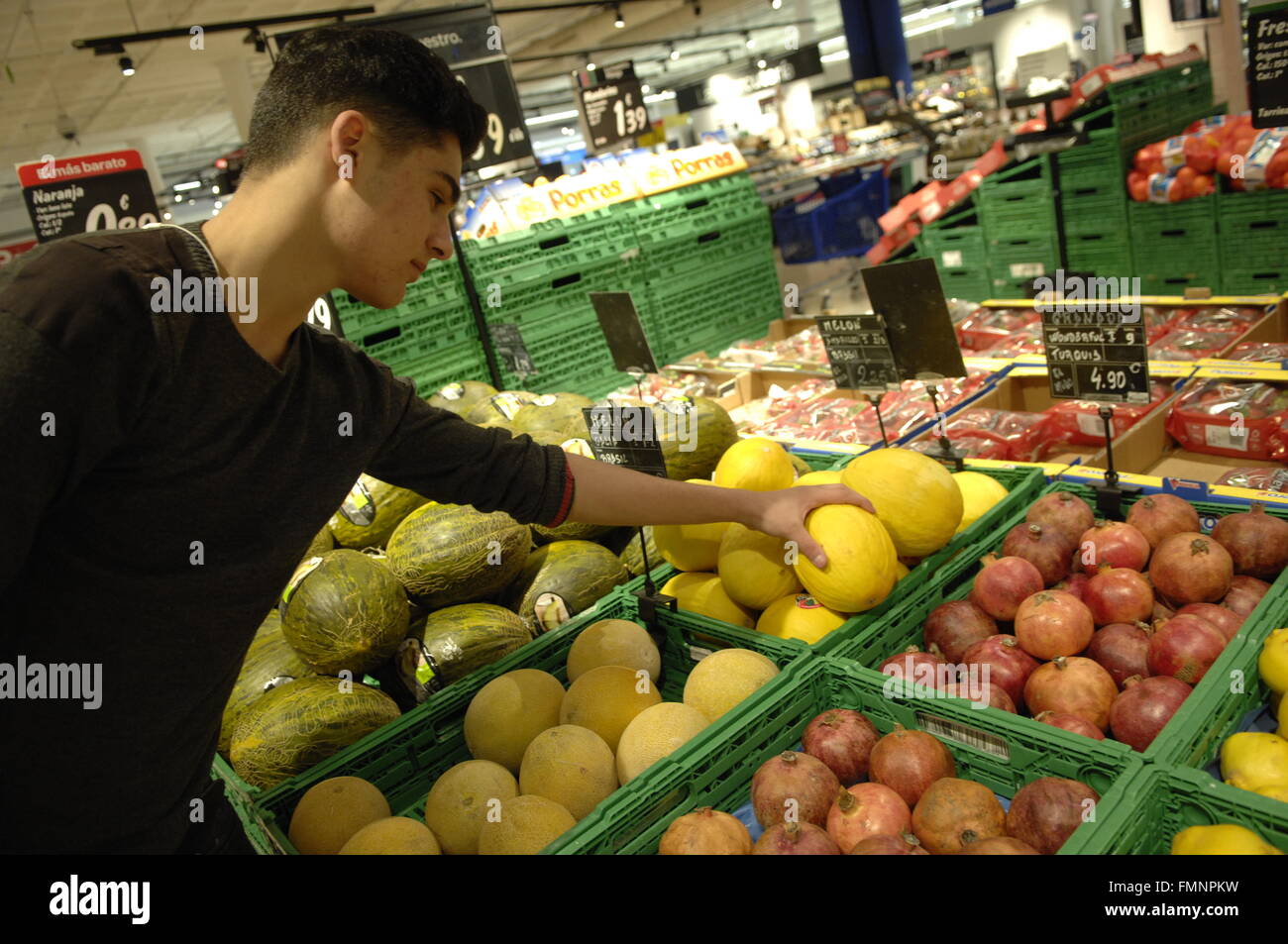 Young man reaching out to grab vegetables in a store Stock Photo - Alamy