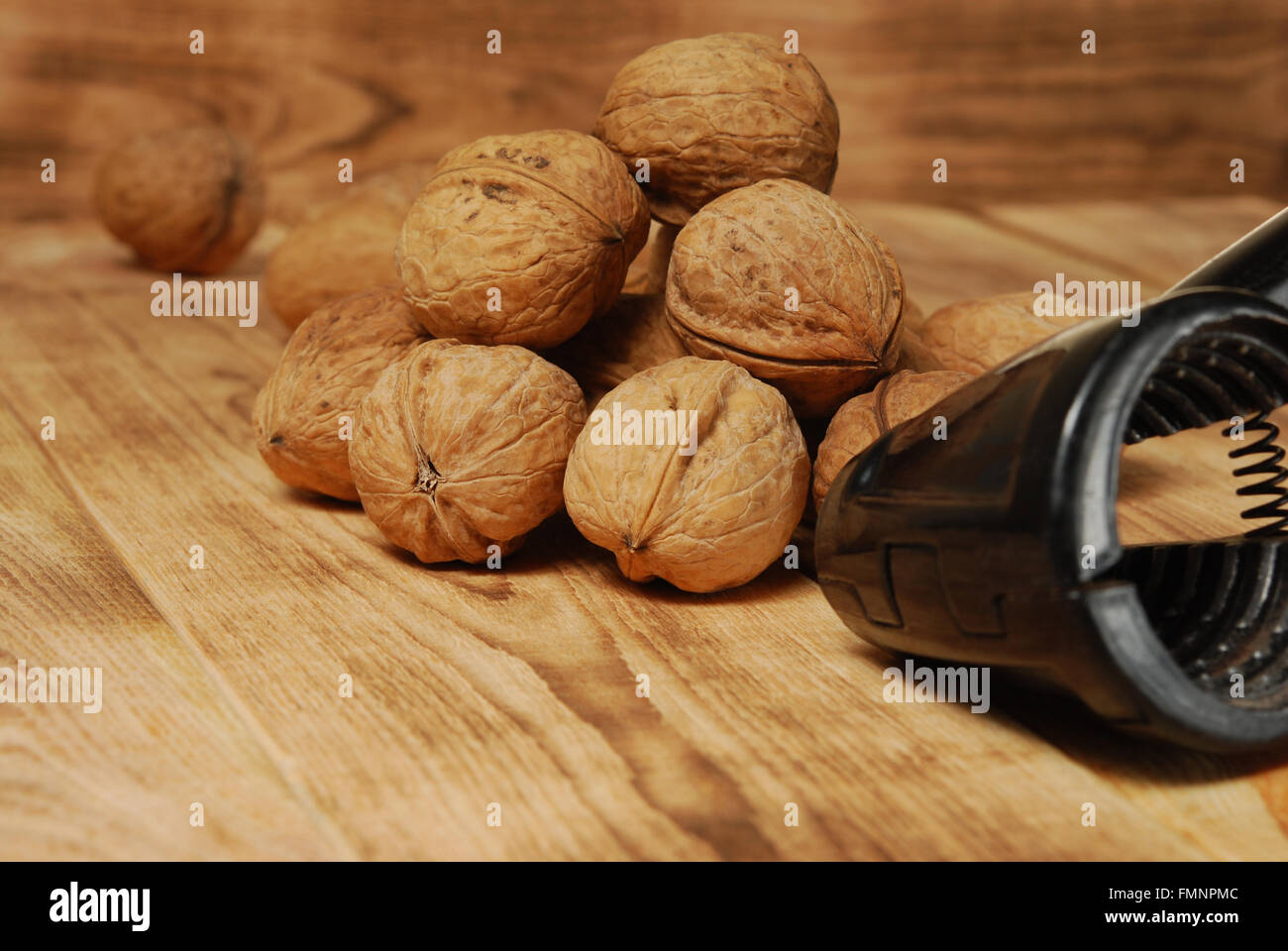 Walnuts on the wooden background with the tool for chopping Stock Photo ...