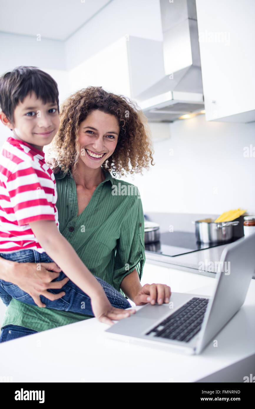 Mother using laptop with son in kitchen Stock Photo - Alamy