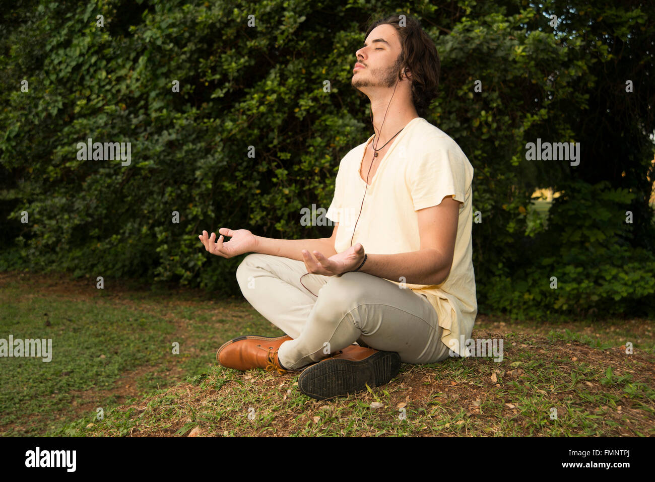 Young man meditating in the outdoors Stock Photo - Alamy