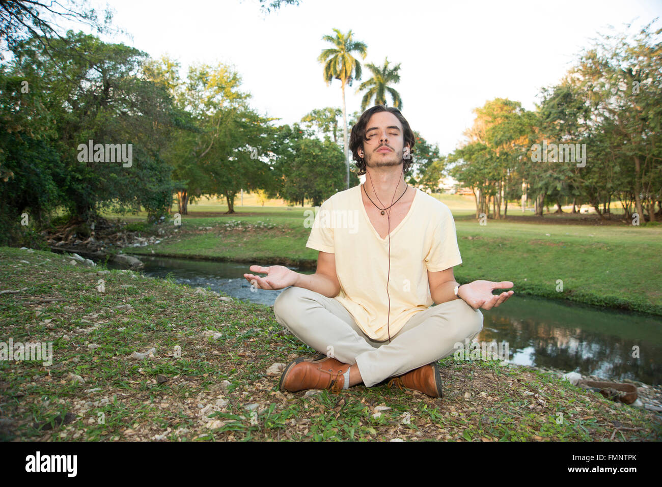 Young man meditating in the outdoors Stock Photo - Alamy
