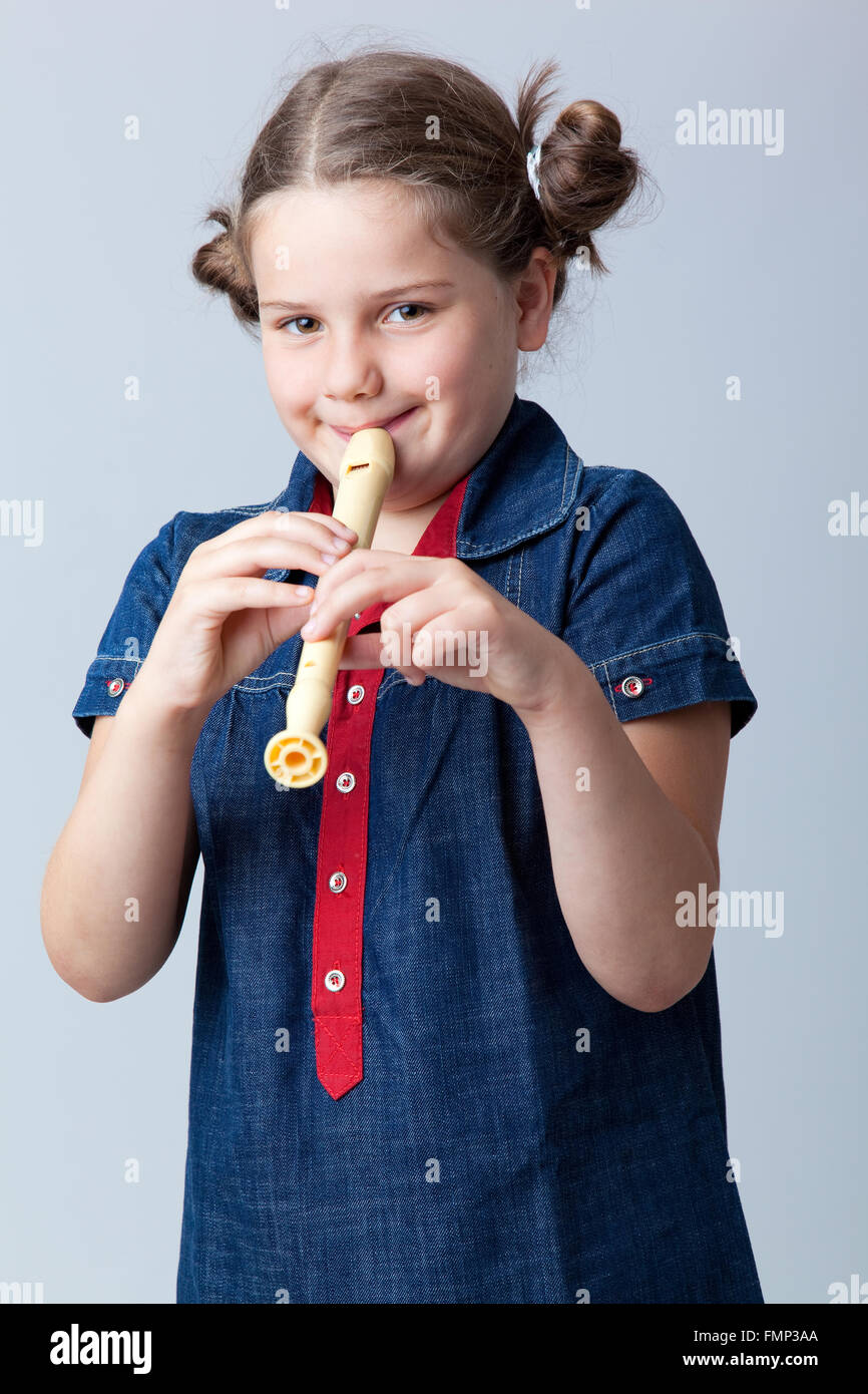 Little girl plays the flute on a grey background Stock Photo - Alamy