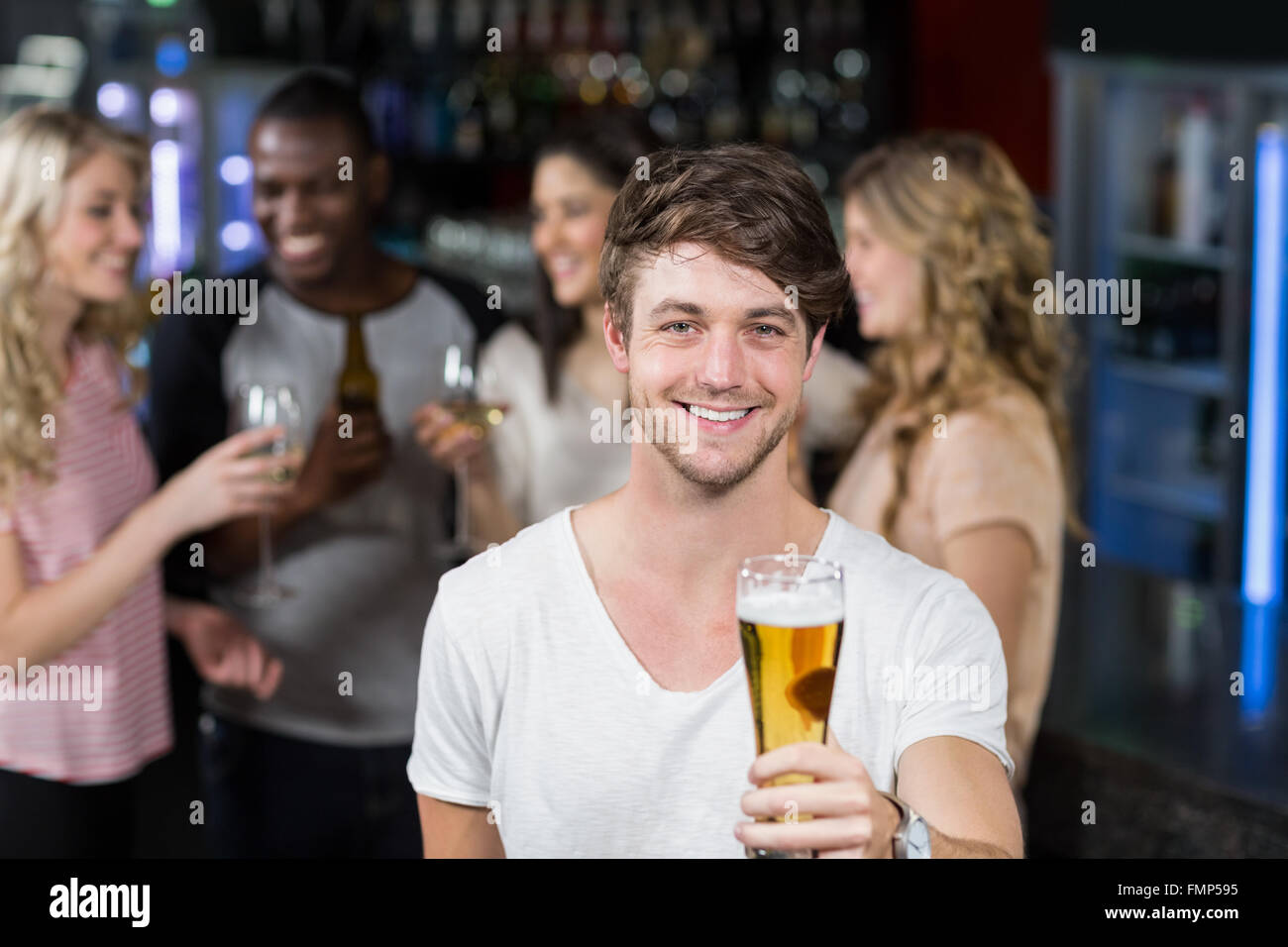 Smiling man showing a beer with his friends Stock Photo - Alamy