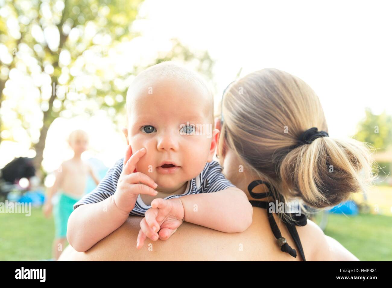 Baby looking over the shoulder of the mother Stock Photo - Alamy