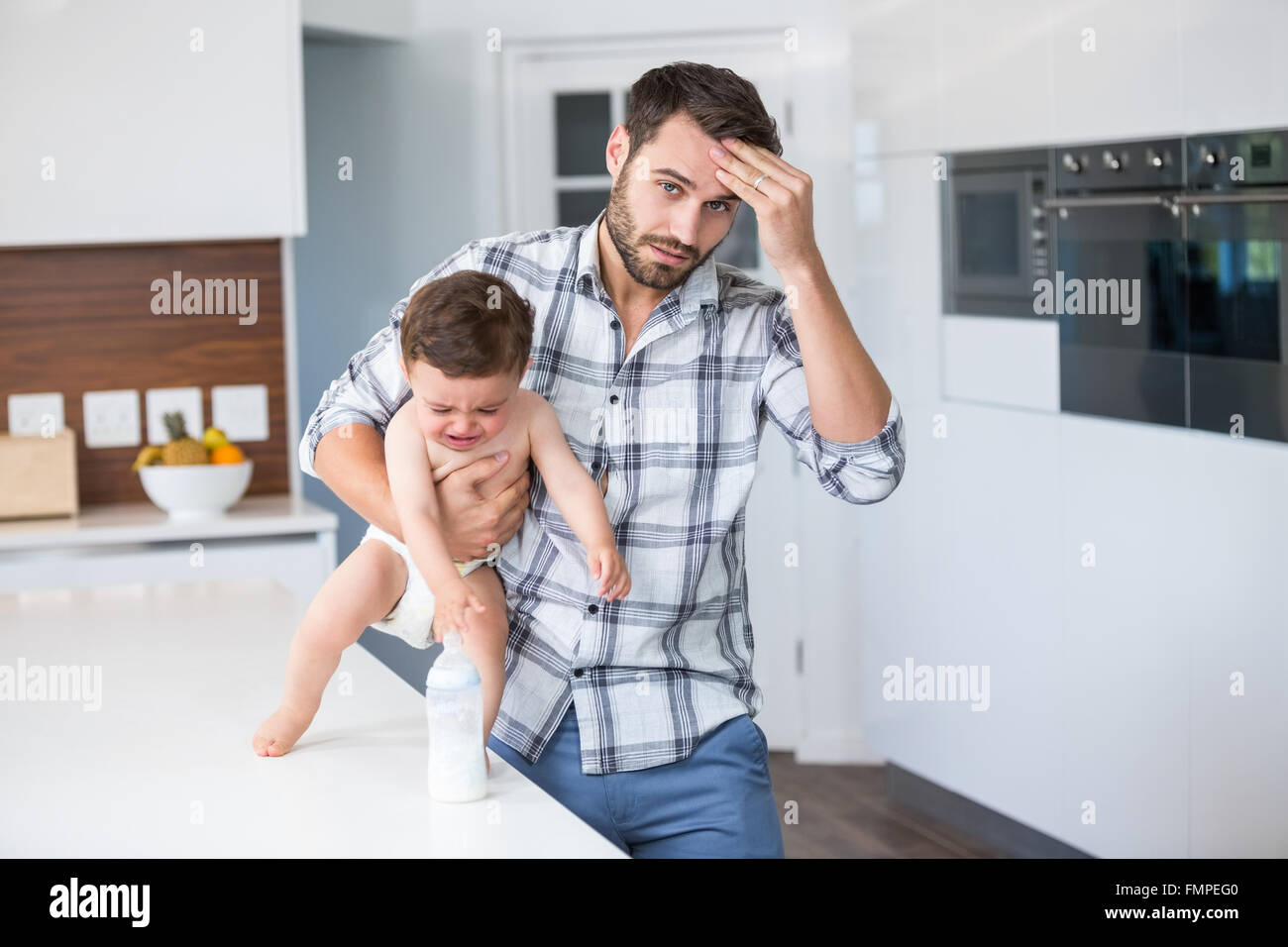 Frustrated father holding crying baby boy Stock Photo - Alamy