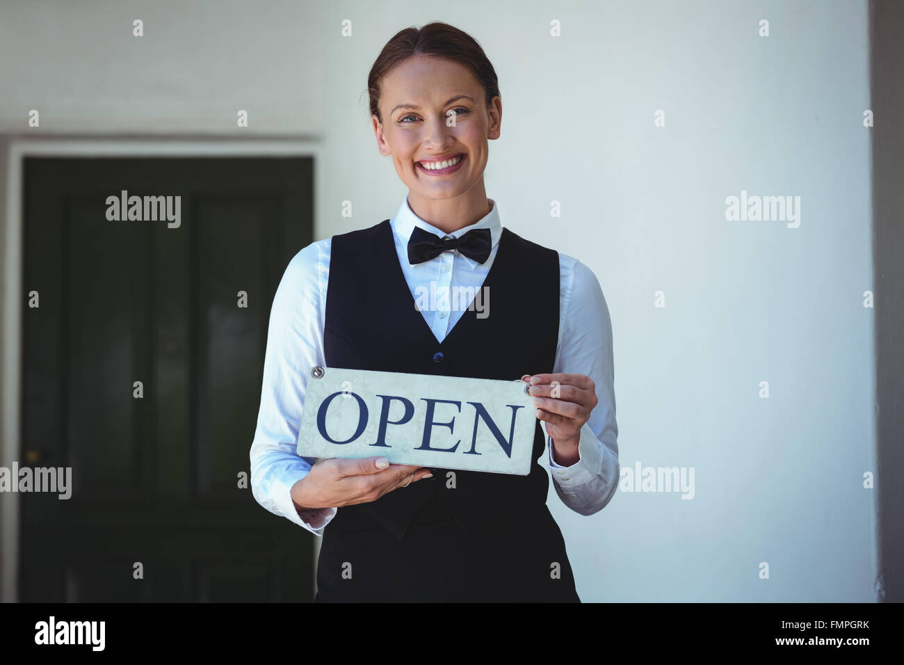 Smiling waitress holding open sign Stock Photo - Alamy