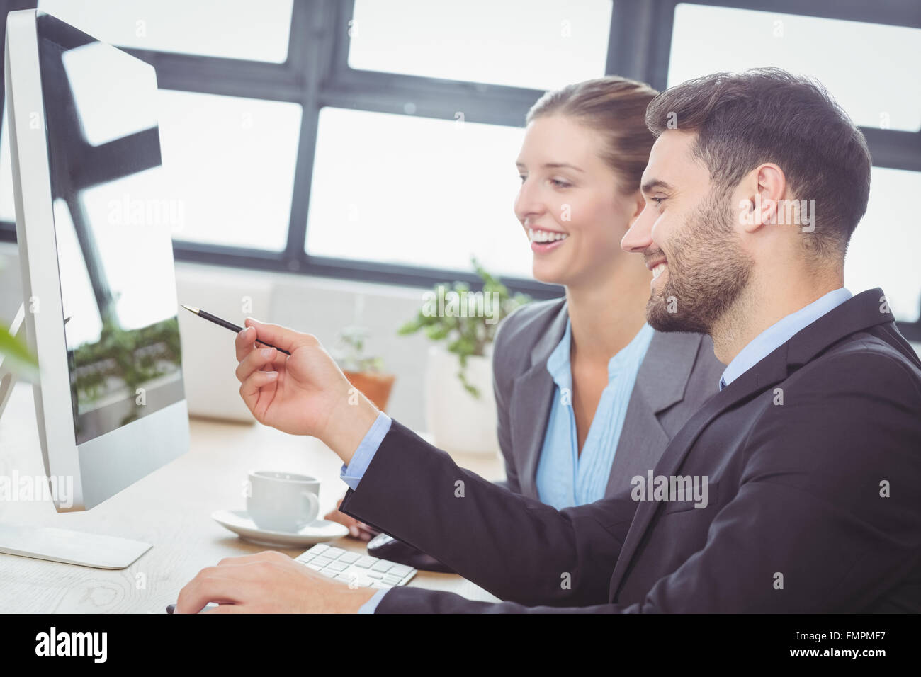 Businessman explaining female colleague at computer desk Stock Photo ...