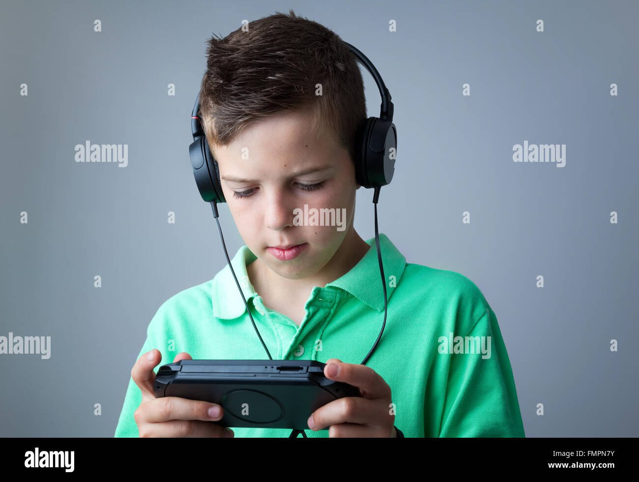 Boy playing game console against grey background Stock Photo - Alamy