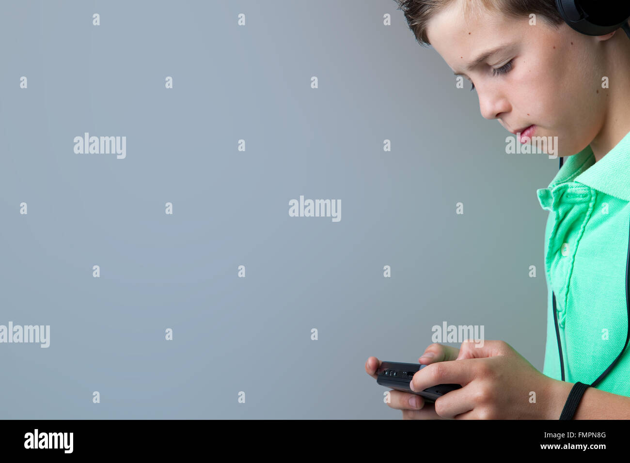 Boy playing game console against grey background Stock Photo - Alamy