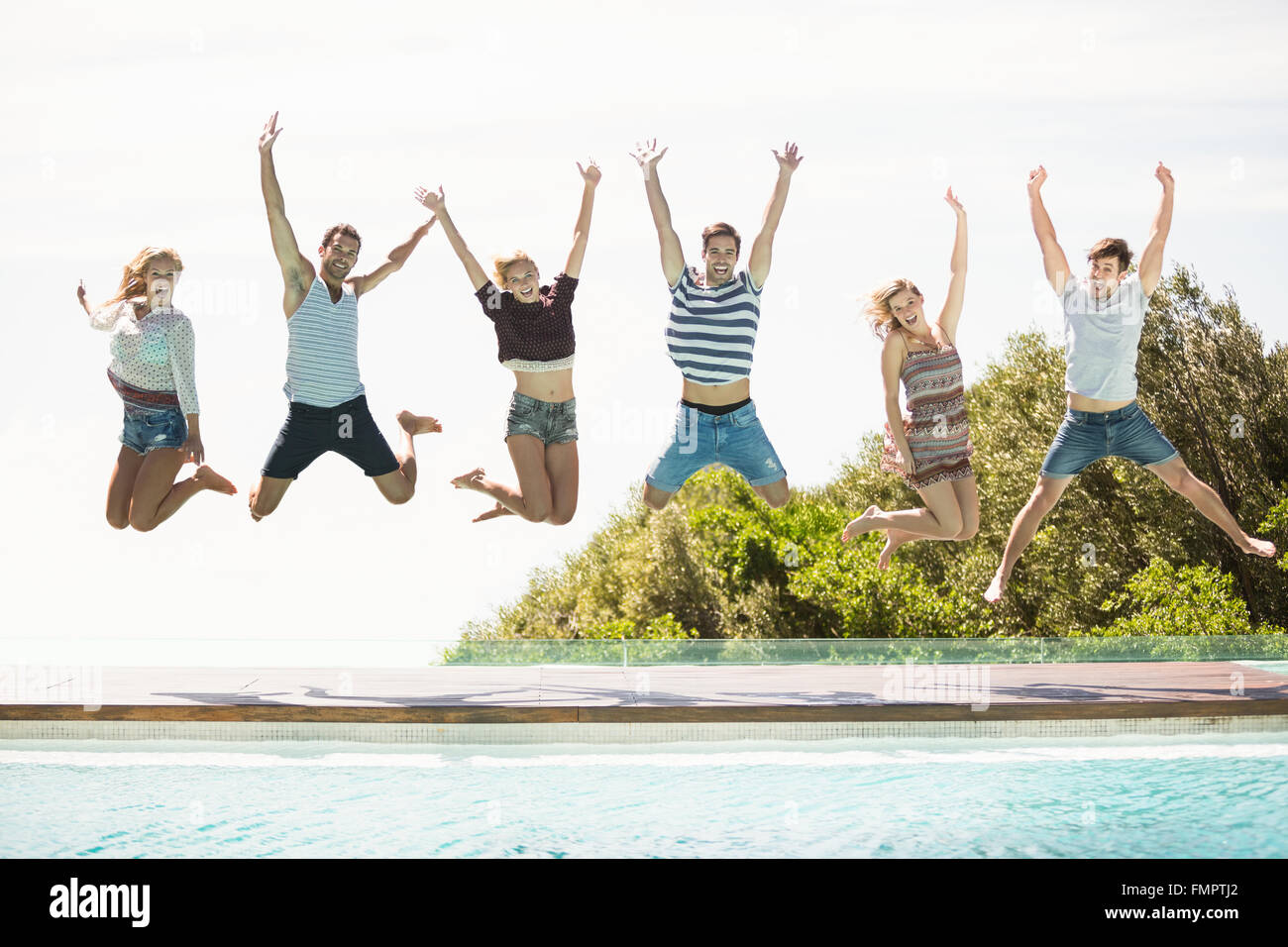 Group of friends jumping at poolside Stock Photo - Alamy