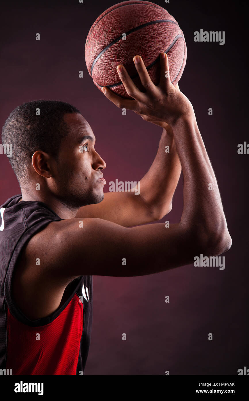 Portrait of a young male basketball player against black background ...