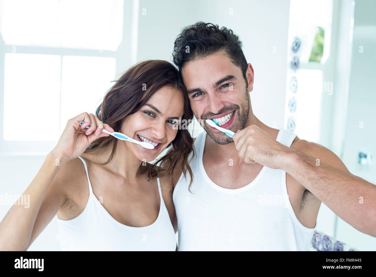 Happy couple brushing teeth in bathroom Stock Photo - Alamy
