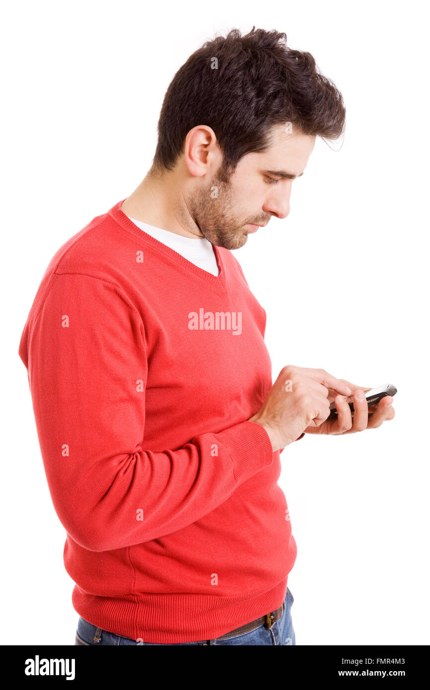 Portrait of a young boy text messaging on mobile phone against white ...