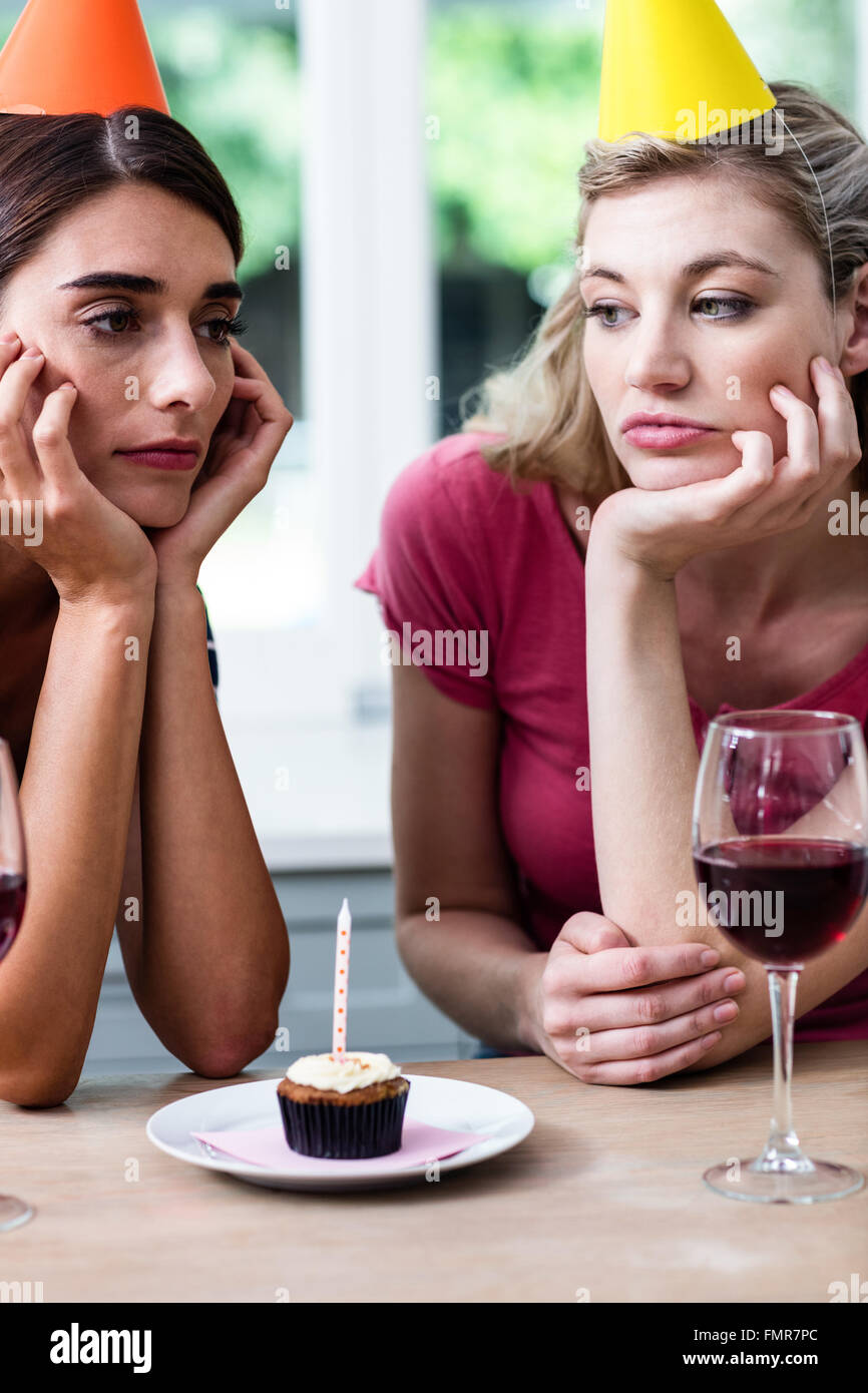 Sad friends sitting at table during birthday party Stock Photo - Alamy