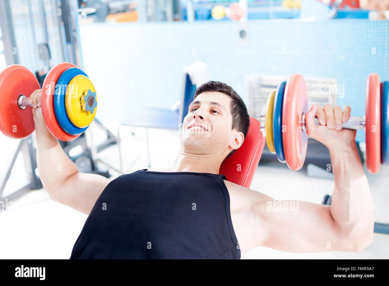 Young handsome man lifting heavy free weights at the gym Stock Photo ...