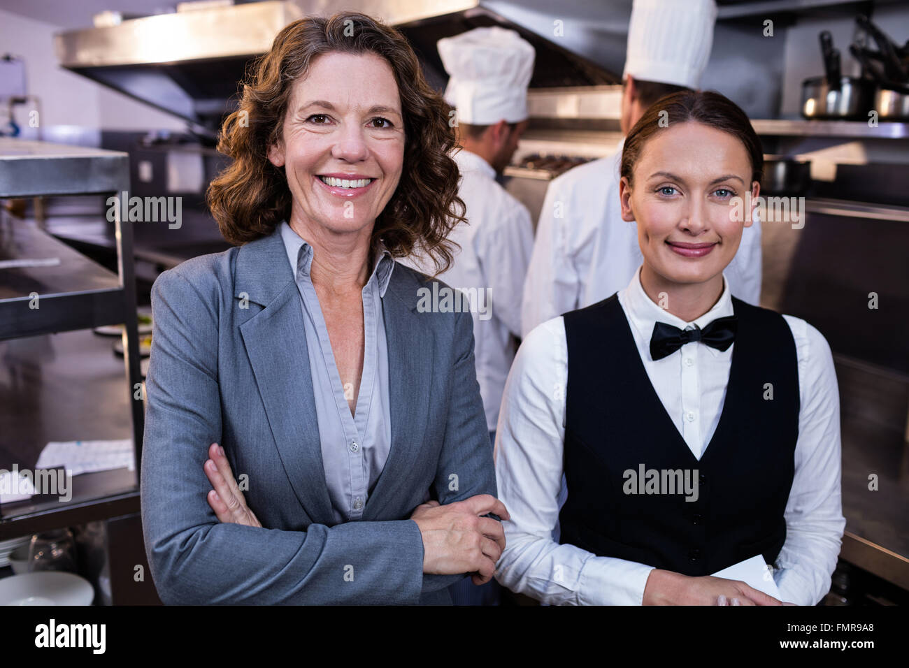 Restaurant manager and waitress smiling in commercial kitchen Stock ...