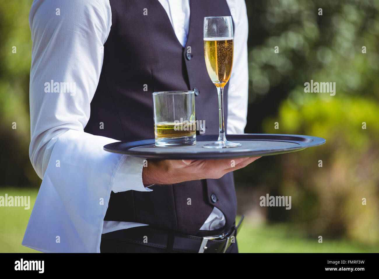 Handsome waiter holding a tray with drinks Stock Photo - Alamy